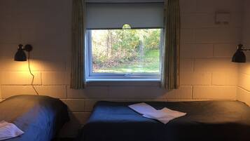 Quarto com duas camas, janela com cortinas e luminárias na parede.
