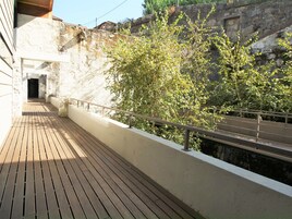 Um deck de madeira com parede de pedra e guarda-corpo de metal.