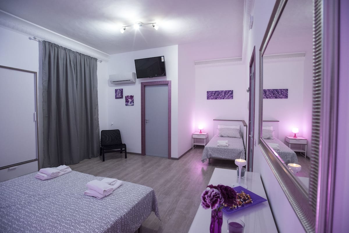 Quarto de hotel com duas camas, televisão, espelho e secretária com abajur.