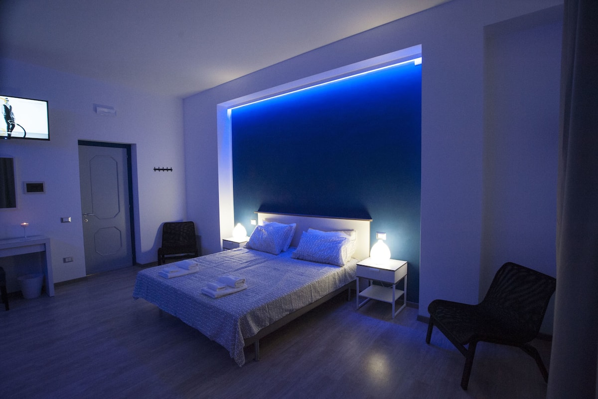 Um quarto moderno com uma cama grande, mesas de cabeceira, uma escrivaninha e uma cadeira.