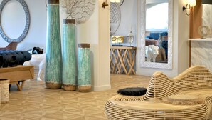Uma sala de estar moderna com um piso estampado em padrões geométricos, um sofá redondo de vime e vasos altos.