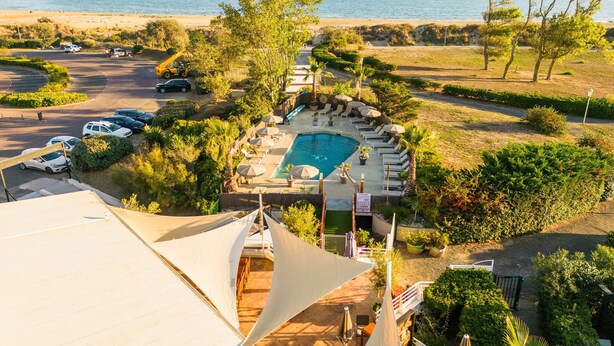 Um resort com piscina, espreguiçadeiras e vista para a praia.