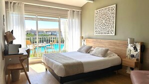 Quarto com uma cama grande, uma escrivaninha e vista para uma piscina.