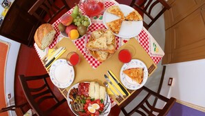 Uma mesa de jantar posta com diversos alimentos e bebidas, cercada por cadeiras.