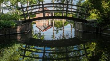 Uma ponte de madeira sobre águas calmas, com um edifício ao fundo.