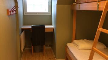 Um quarto de estudante com uma cama beliche, uma escrivaninha com cadeira e uma janela.