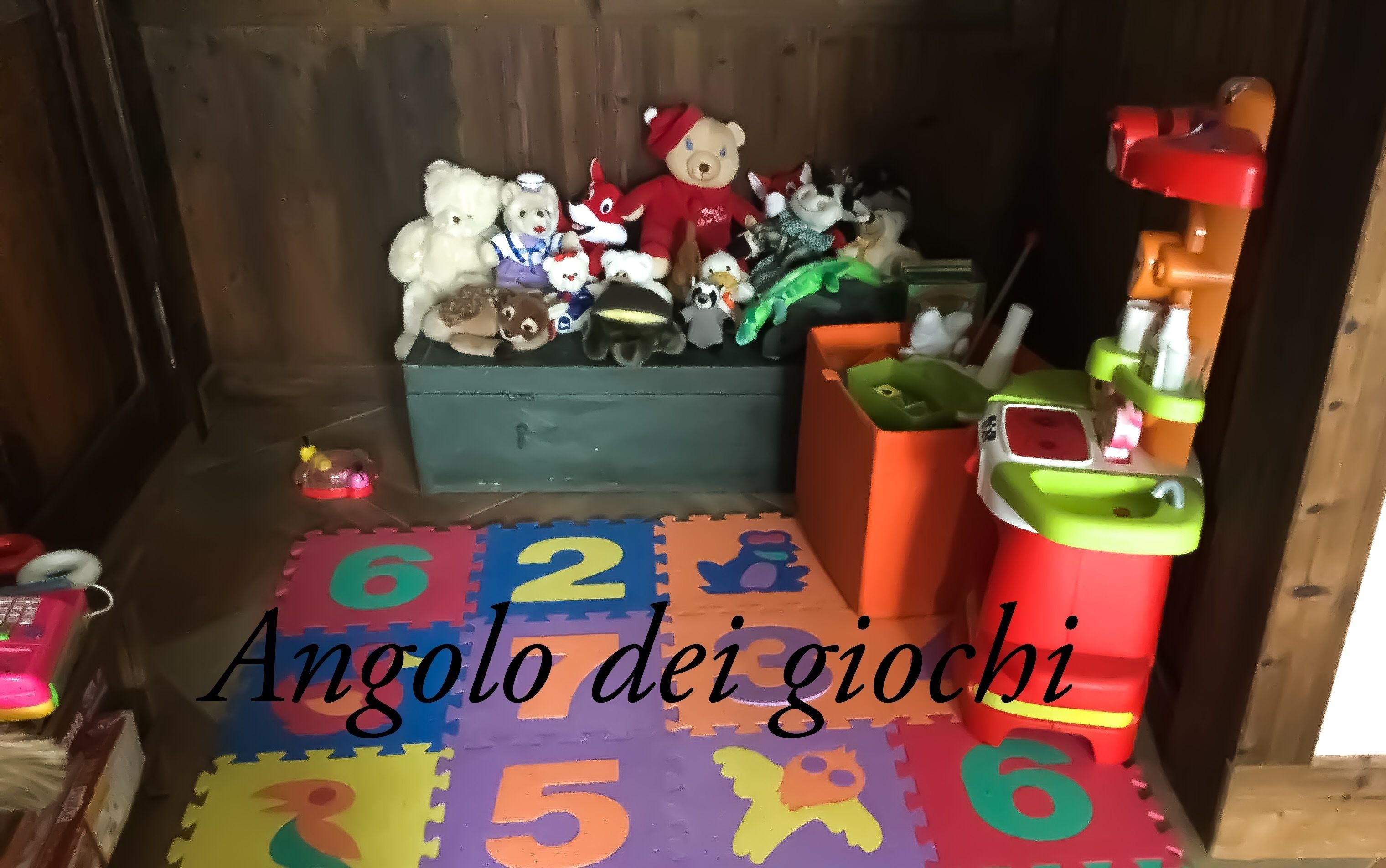 Uma área de recreação infantil com diversos brinquedos e um tapete de quebra-cabeças.