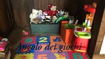 Uma área de recreação infantil com diversos brinquedos e um tapete de quebra-cabeças.