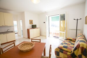 Um espaço compacto com cozinha compacta, área de refeições e sofá.