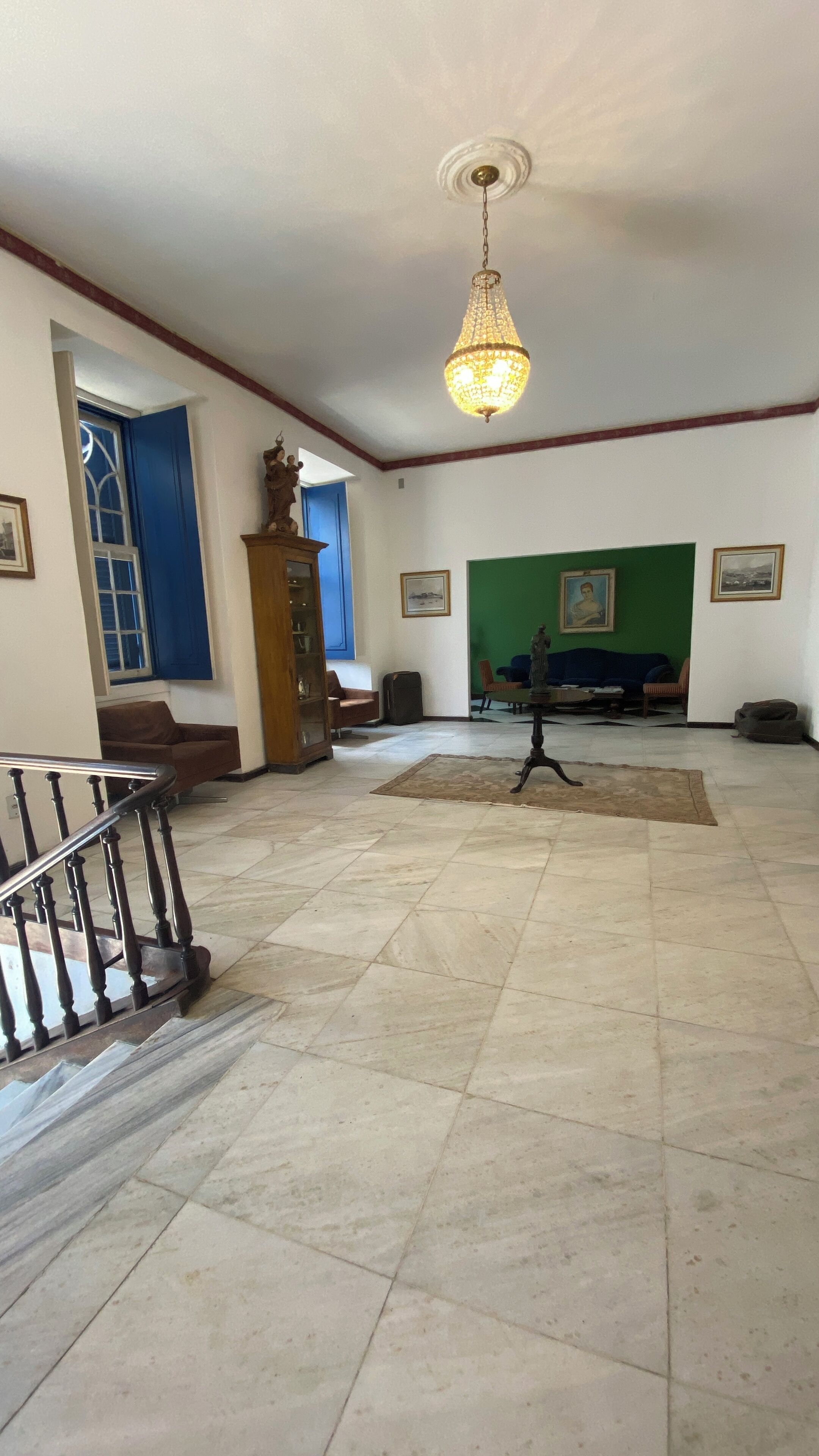 Uma sala de estar espaçosa com um candelabro, uma parede verde e uma escada.