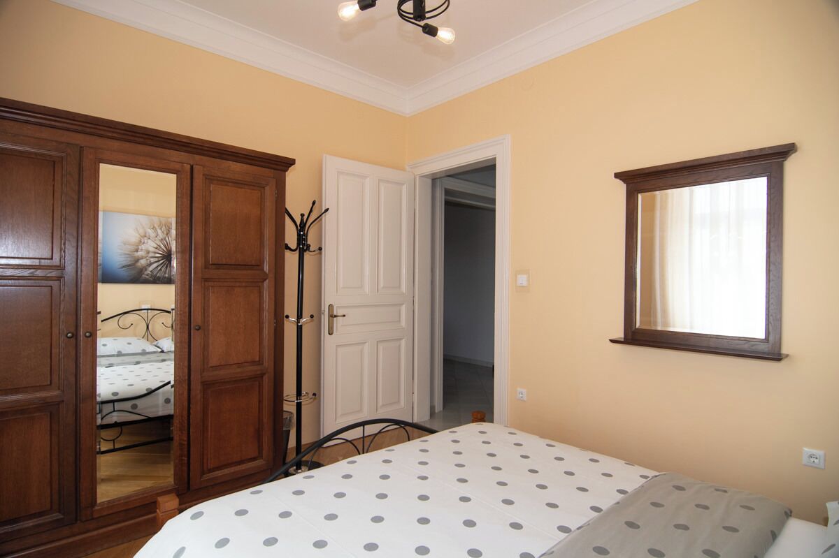 Quarto com cama, guarda-roupa, cabideiro e janela.