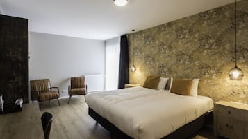 Quarto moderno com uma cama grande, duas cadeiras, uma escrivaninha de madeira e uma mesa de cabeceira.