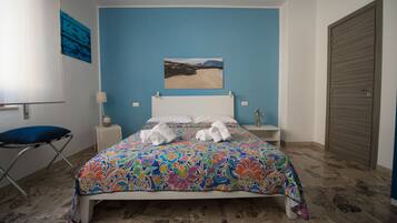 Quarto com cama, cadeira, mesa de cabeceira, abajur e porta.