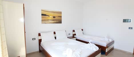 Quarto de hotel com duas camas, um quadro na parede e uma porta.
