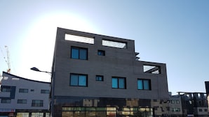 Um edifício moderno com telhado plano, janelas amplas e uma guindaste de construção ao fundo.
