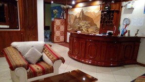 Uma sala de estar com um sofá, uma mesa de centro e um balcão de atendimento de madeira.