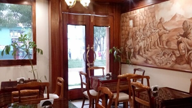 Um restaurante com móveis de madeira, um mural e um candelabro.