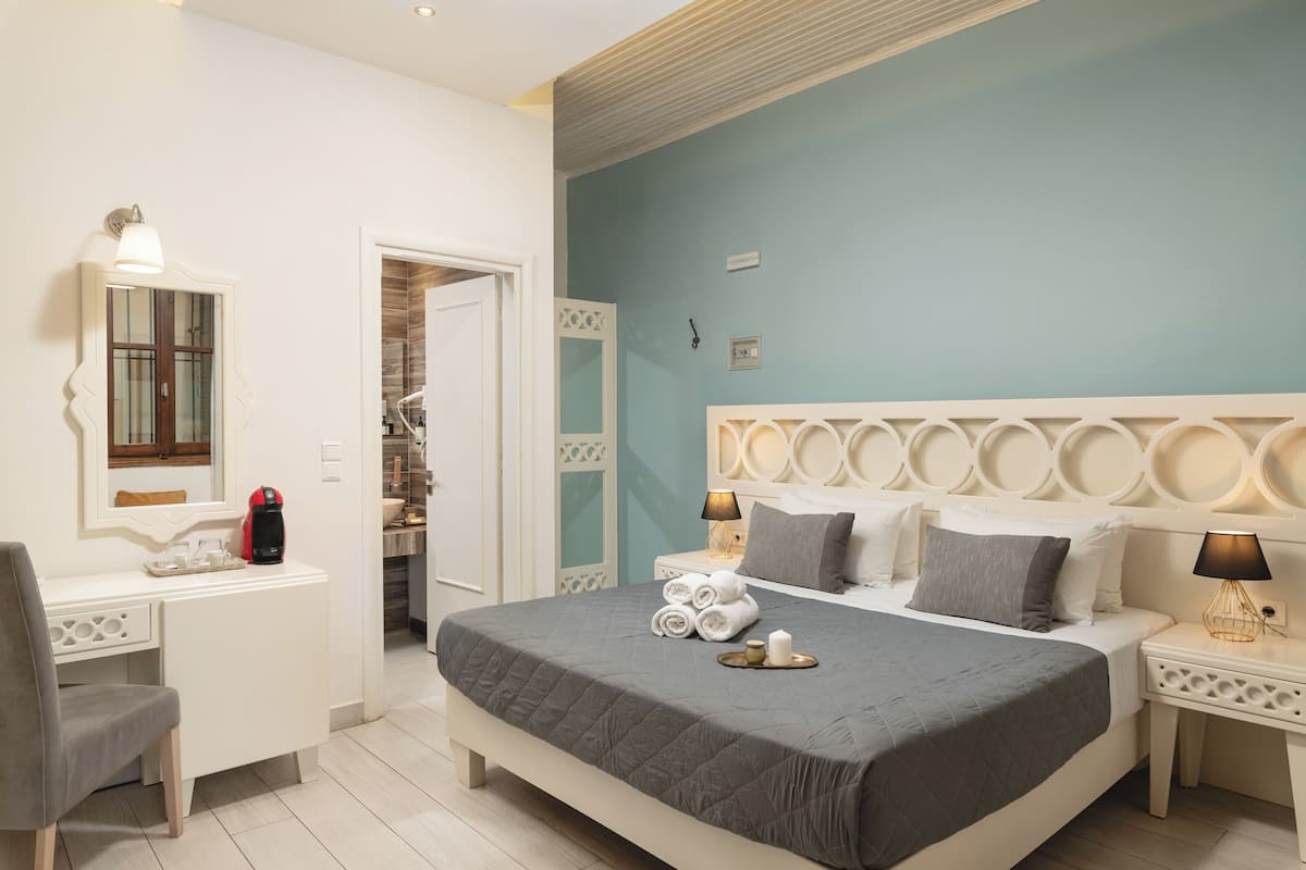 Quarto com cama, mesas de cabeceira, escrivaninha e uma cadeira.