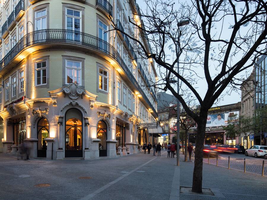 Um edifício histórico com arquitetura elaborada, rua de paralelepípedos e área para pedestres.