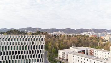 Um edifício moderno com fachada geométrica, rodeado por uma paisagem urbana e montanhas ao fundo.