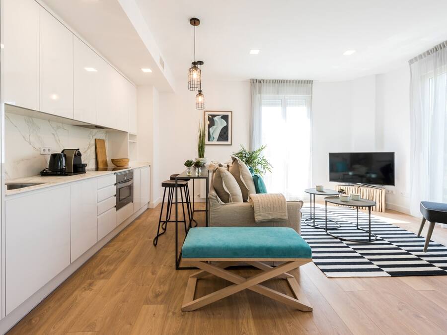 Um apartamento moderno com cozinha, sala de estar e televisão.
