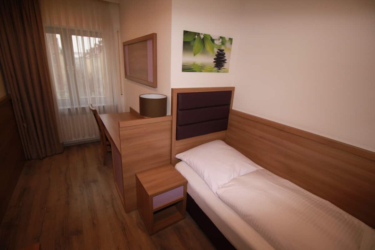 Quarto de hotel bem arrumado com cama, escrivaninha e cadeira.