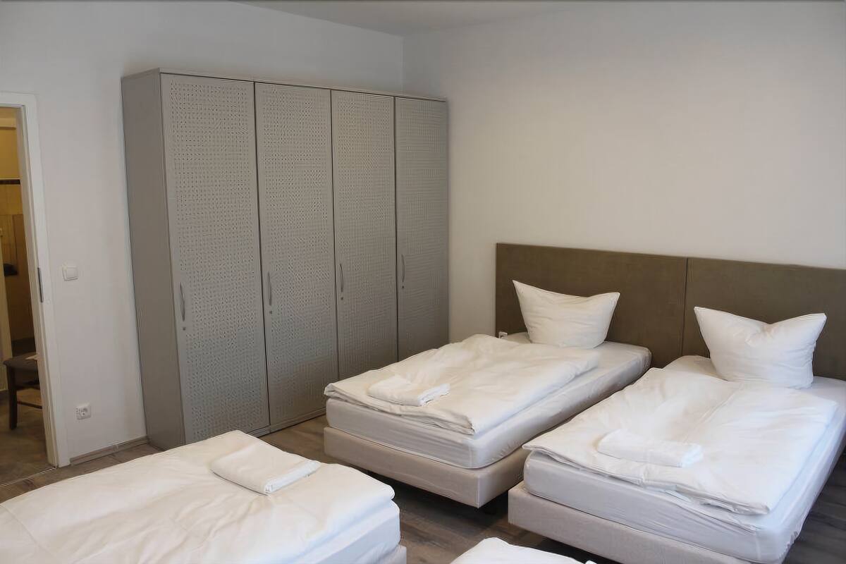 Quarto de hotel com duas camas de solteiro, um guarda-roupa espaçoso e um pequeno espaço para sentar.