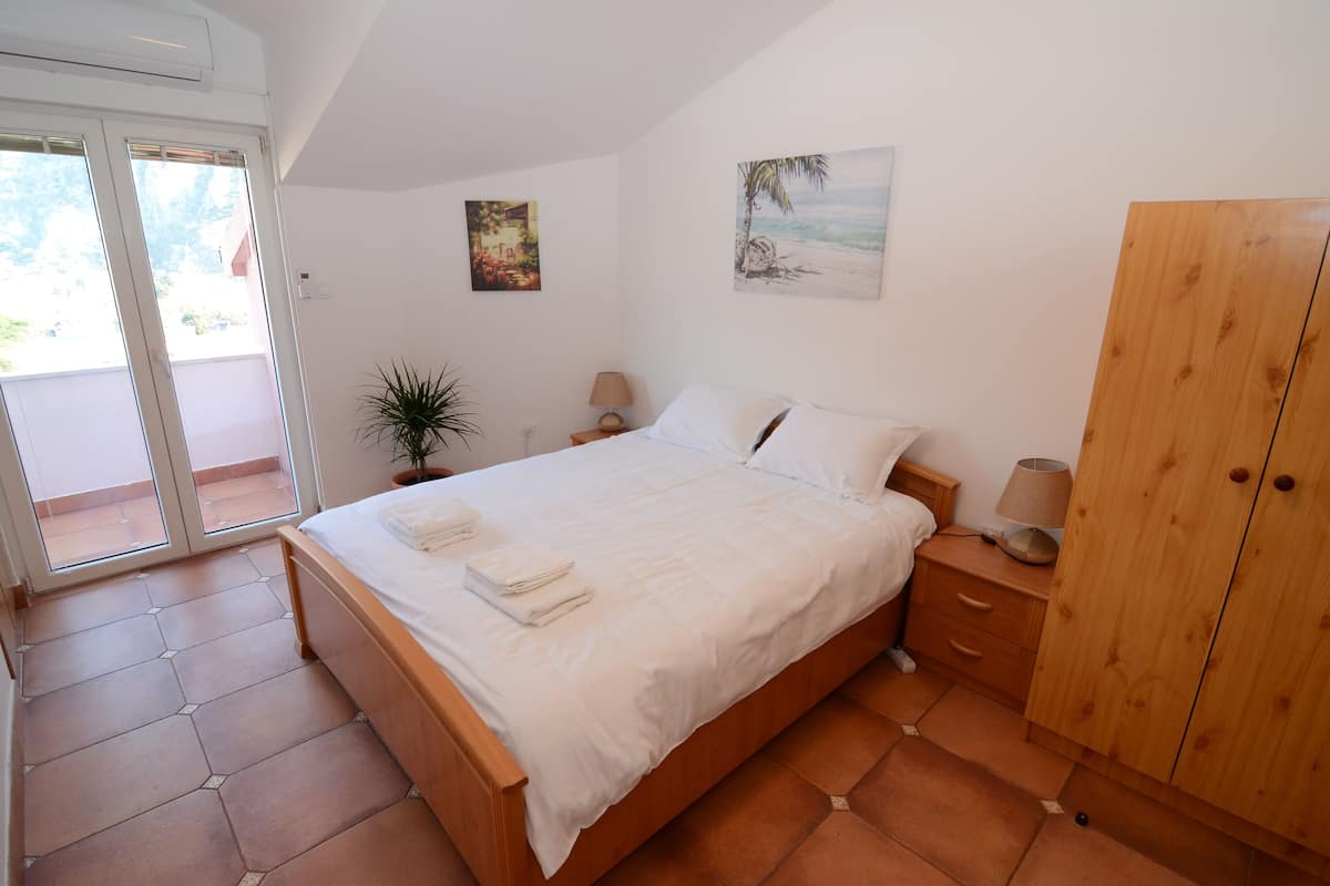 Quarto com cama, mesas de cabeceira, guarda-roupa, planta em vaso e um quadro na parede.