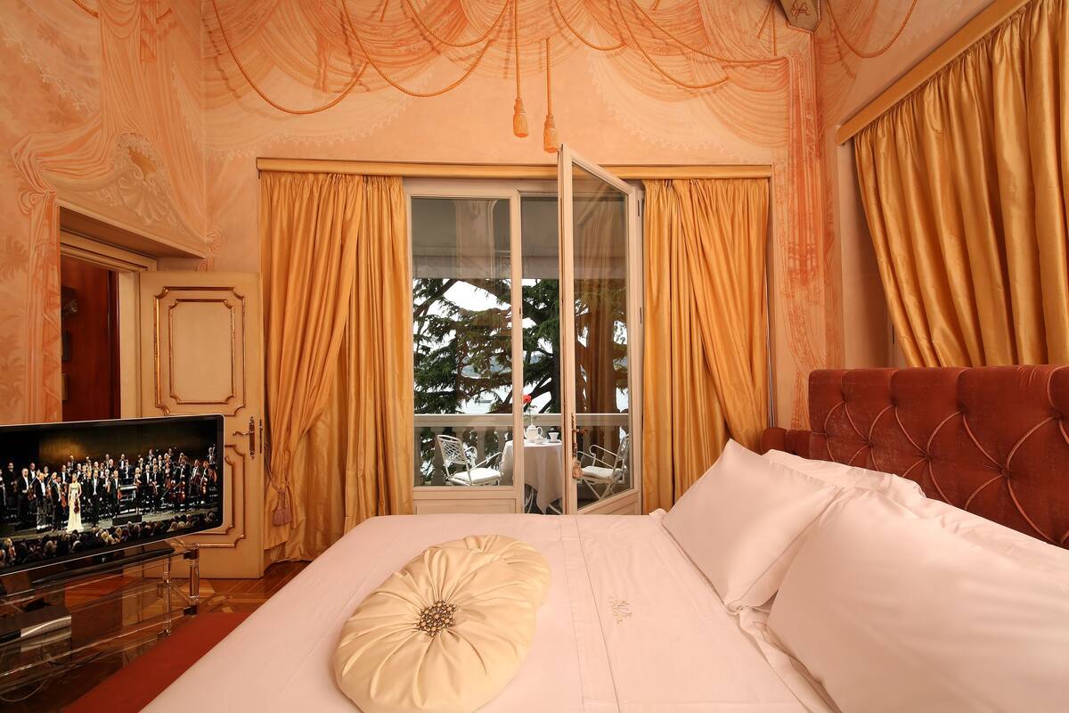 Quarto com uma cama grande, televisão e janela com cortinas.