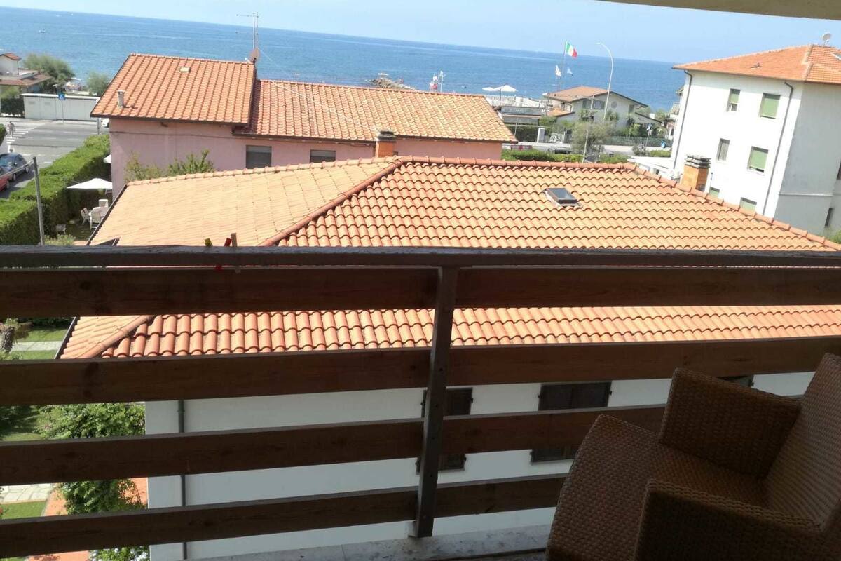 Varanda com telhado ladrilhado com vista para área costeira, edifícios e o mar.
