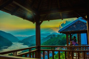 Uma estrutura de madeira com vista para um rio e montanhas.