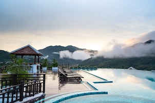 Um deck de madeira com piscina, um gazebo e montanhas ao fundo.
