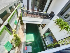 Um edifício moderno com um jardim no terraço, uma piscina pequena e uma varanda com guarda-corpo.