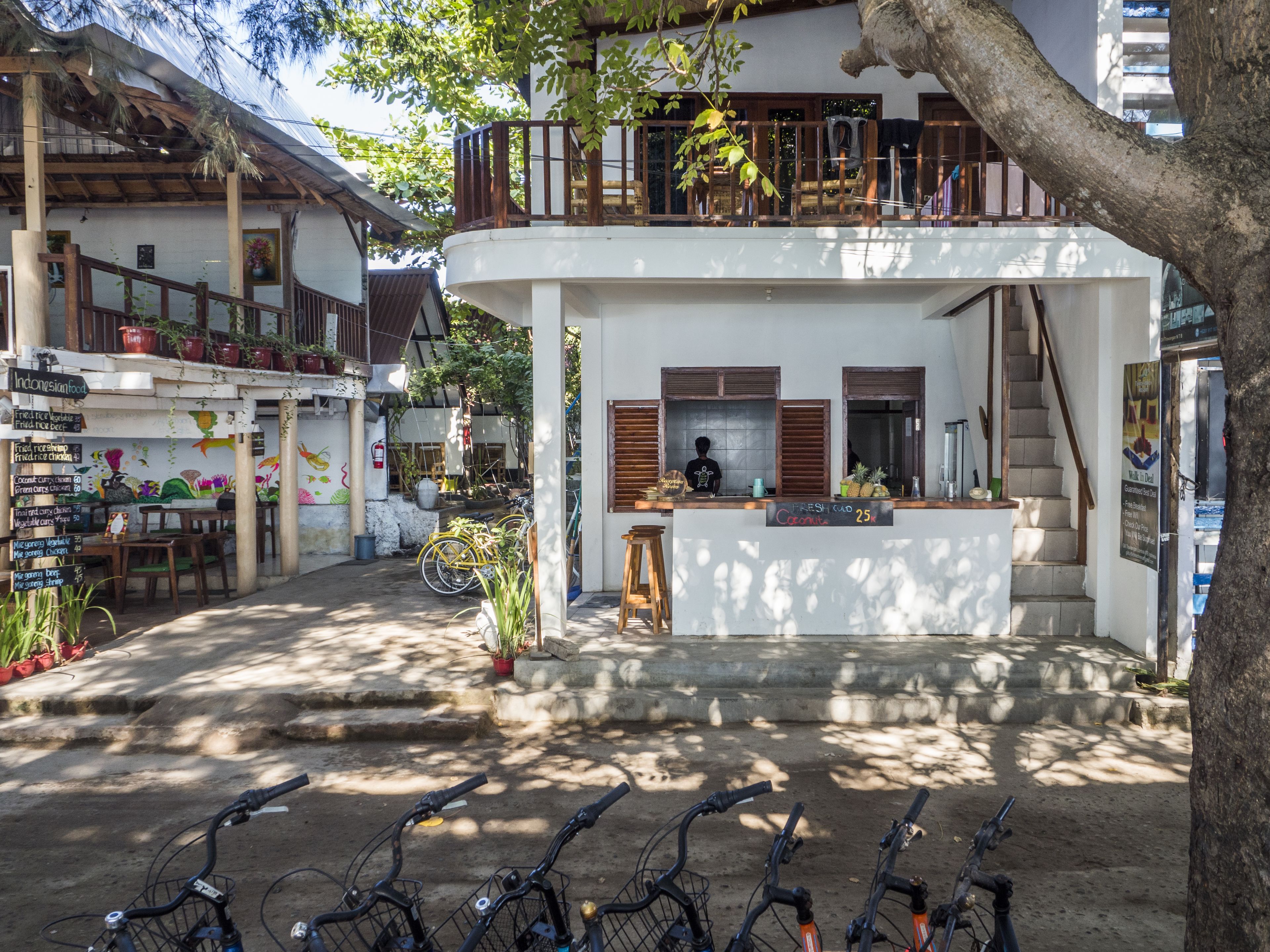 Um pátio com um edifício branco, uma escadaria de madeira e bicicletas estacionadas em frente.