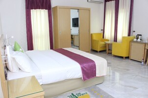 Quarto de hotel com cama, escrivaninha, cadeira e guarda-roupa.