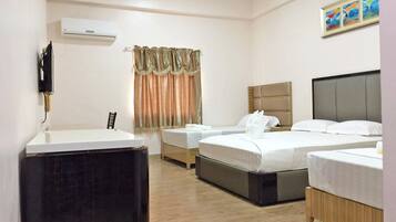 Quarto de hotel com uma cama grande, uma cama menor, uma escrivaninha com cadeira e um banheiro com pia e espelho.