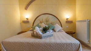 Cama bem arrumada com colcha acolchoada, cabeceira decorativa e mesa de cabeceira com abajur.