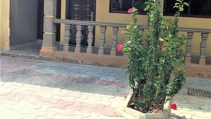 Um edifício com fachada de pedra, duas janelas, uma varanda e um vaso com flores cor-de-rosa.