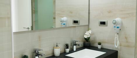 Uma casa de banho moderna com duas pias, um espelho grande e um secador de cabelo fixado na parede.