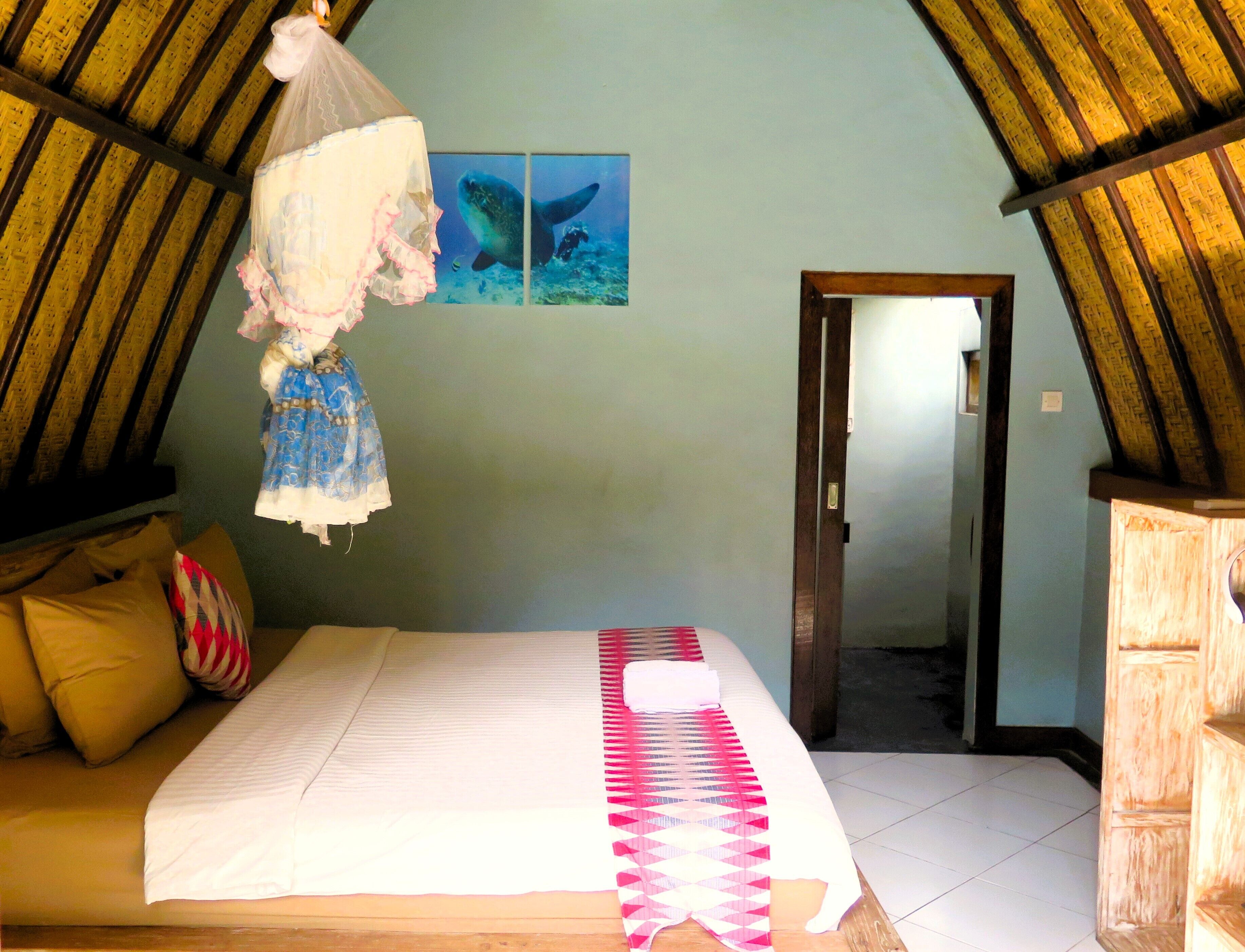 Quarto com cama, cadeira suspensa e um mural com um esboço de baleia.