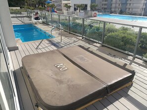 Uma espreguiçadeira em um deck com uma piscina ao fundo.