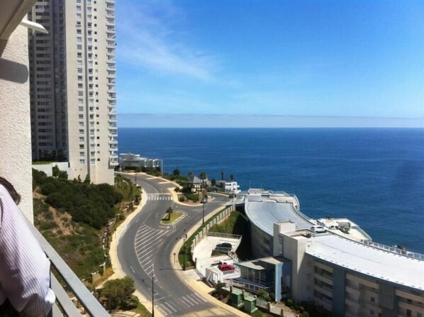 Paisagem costeira com uma estrada sinuosa, edifícios altos e vista para o mar.