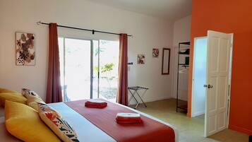 Quarto com cama, janela com cortinas, um varal e porta que dá para outro cômodo.