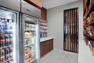 Uma cozinha compacta com geladeira abastecida com bebidas, micro-ondas e máquina de café.