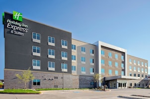 Um hotel Holiday Inn Express & Suites com fachada moderna, várias janelas e estacionamento.