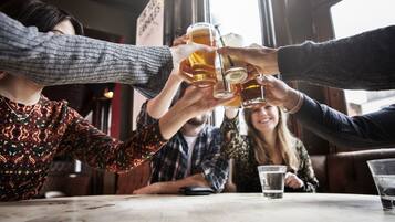 Um grupo de pessoas brindando com copos de cerveja em uma mesa, em um restaurante.