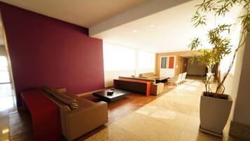 Uma sala de estar moderna com uma parede de destaque vermelha, um sofá modular, uma mesa de centro e um vaso de planta.