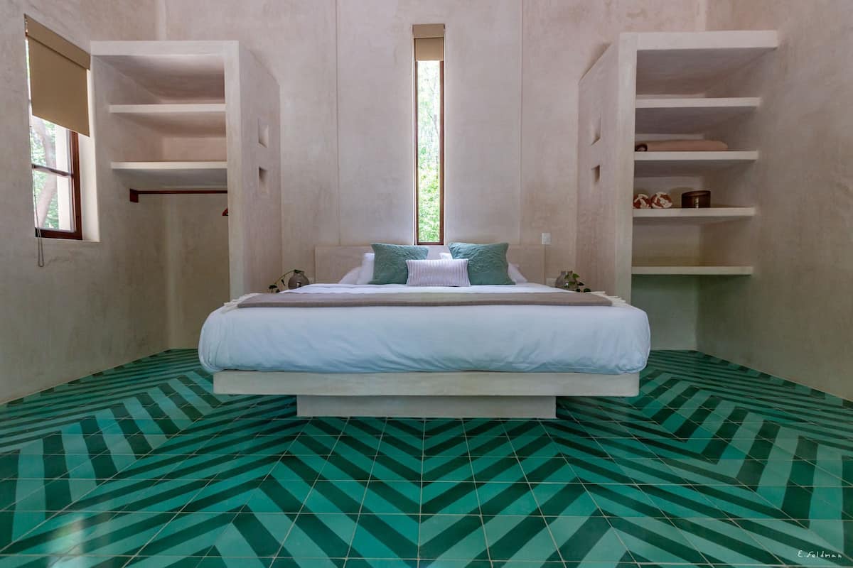 Quarto com cama grande, prateleiras embutidas e piso estampado.
