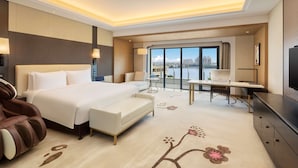 Quarto de hotel moderno com uma cama grande, um sofá, uma escrivaninha e uma televisão.