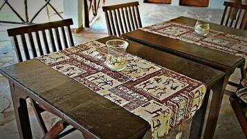 Uma mesa de madeira com toalha de mesa estampada e um jarro de vidro.